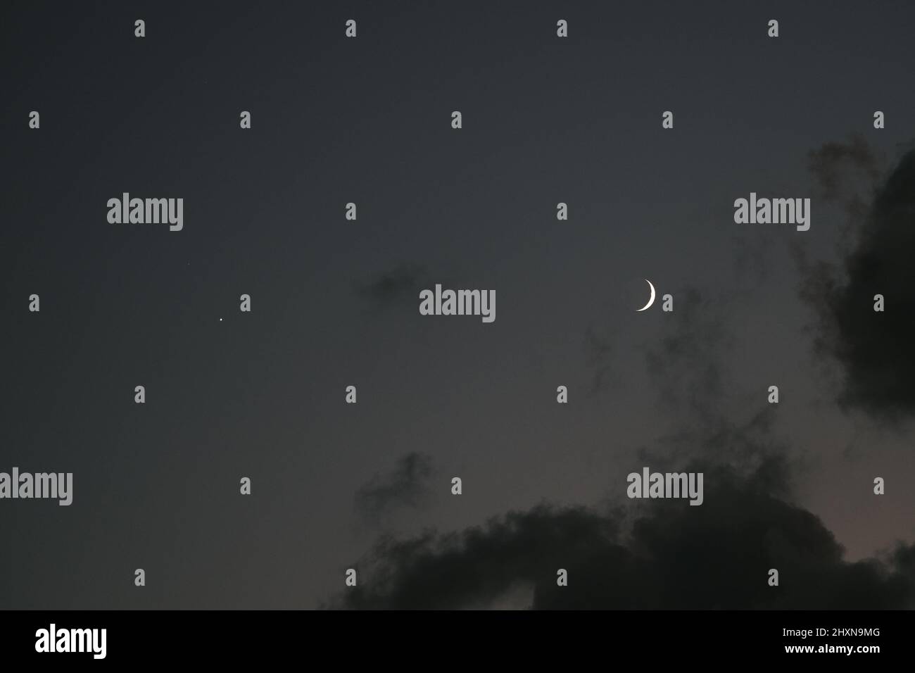 The crescent moon in the cloudy sky, rising in the east Stock Photo - Alamy