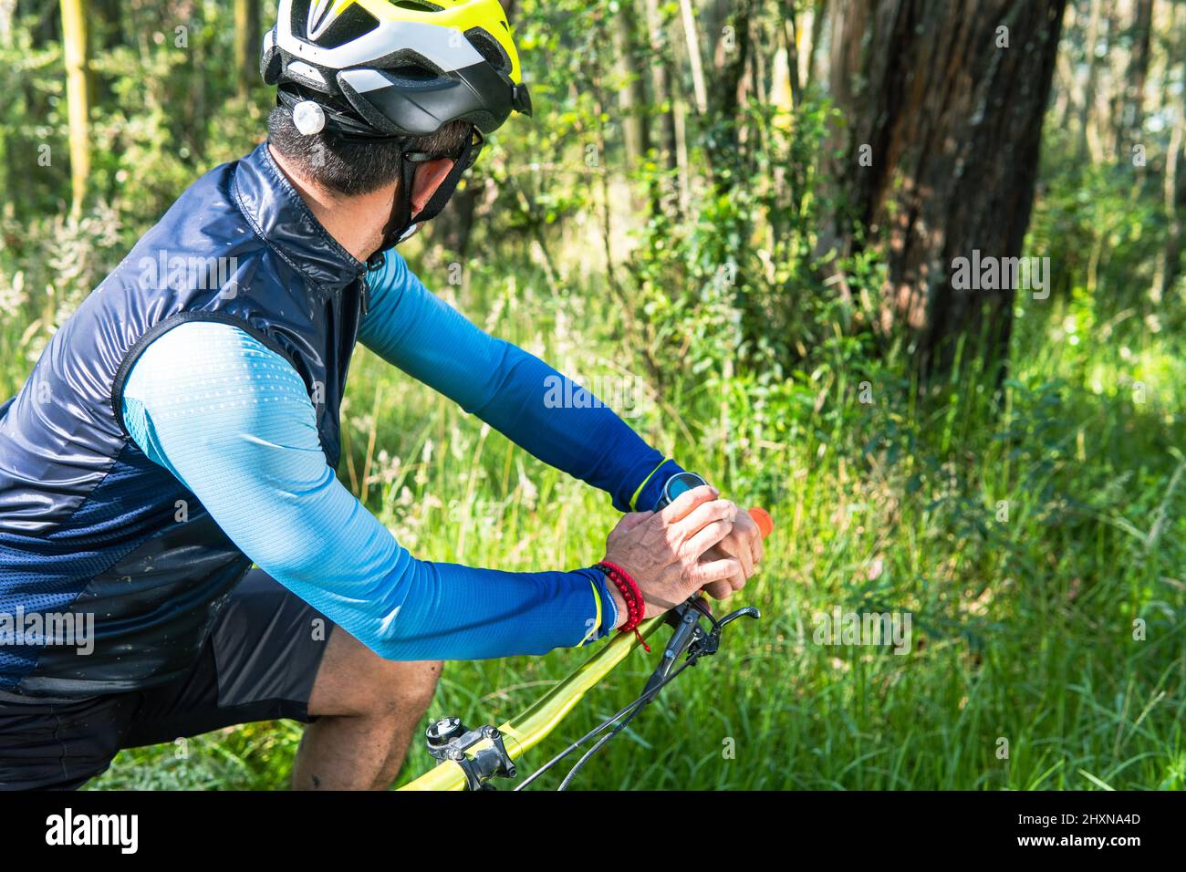 Detail of man on his back on his mountain bike checking his smart watch ...
