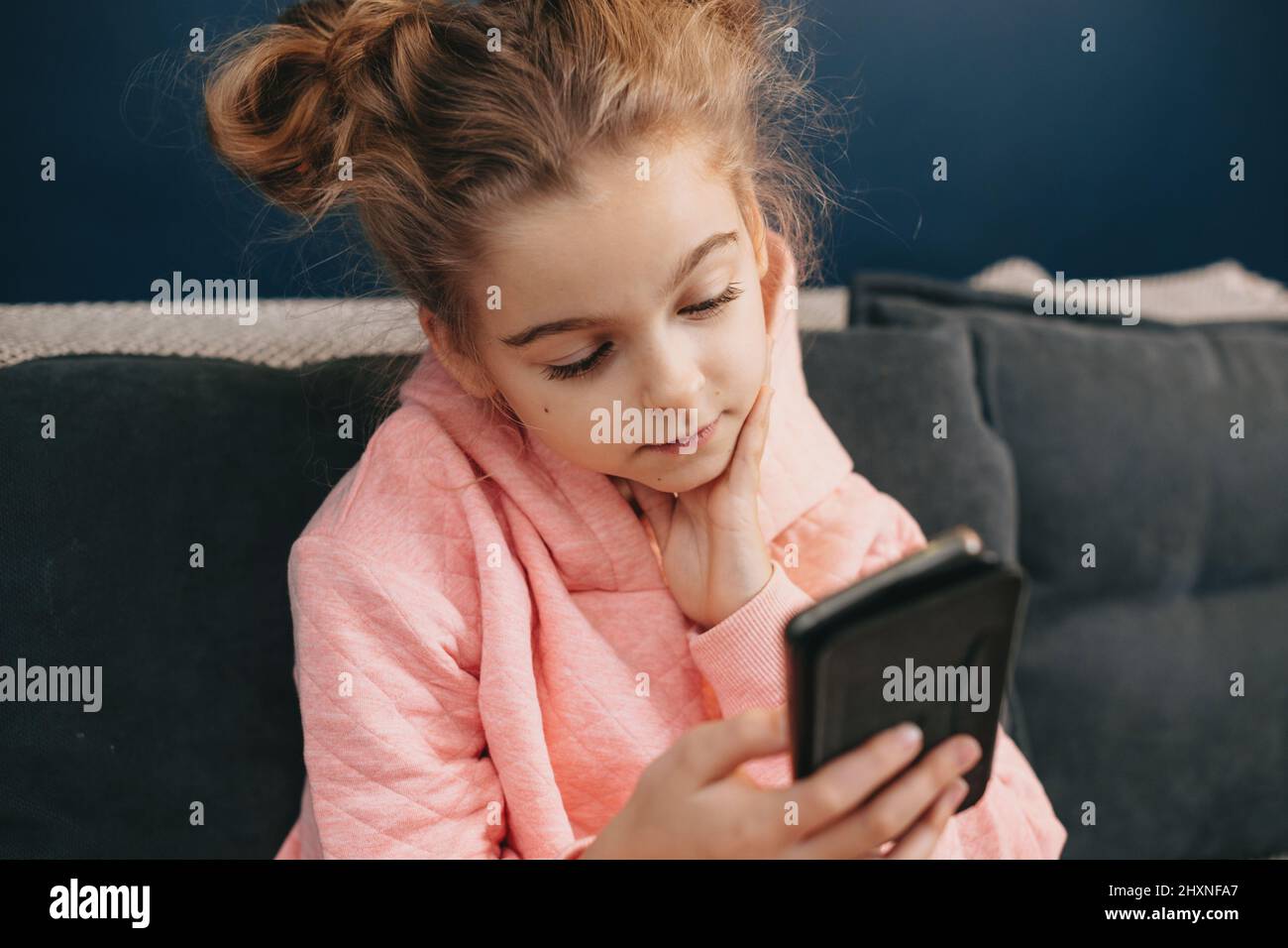 Close up portrait of a Caucasian girl child looking at cellphone screen ...