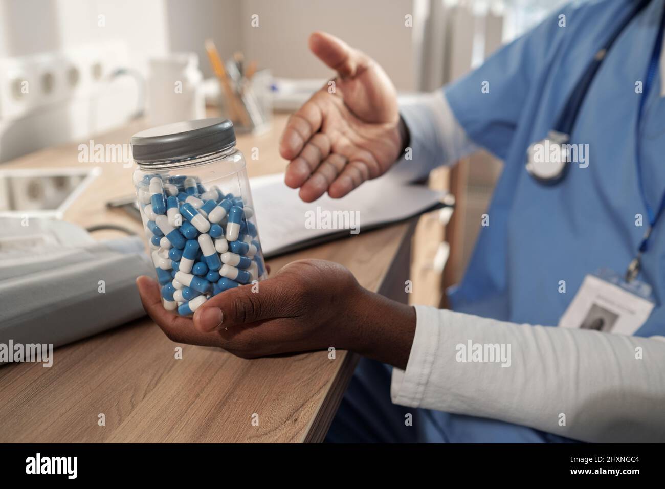 Hands of young African American male clinician holding jar with white ...