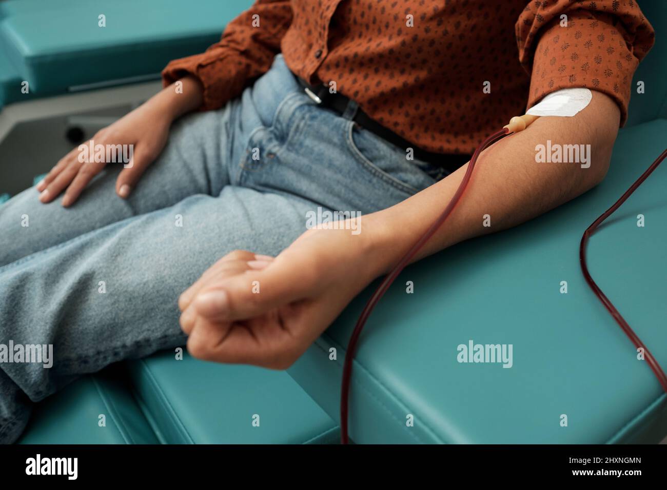 Close-up of young female donor in casual clothes giving her blood ...