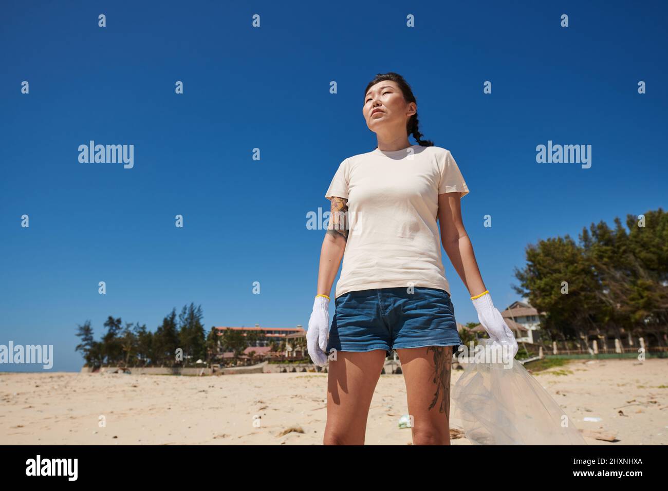 Determined woman with big plastic bag in hand looking at dirty sandy ...