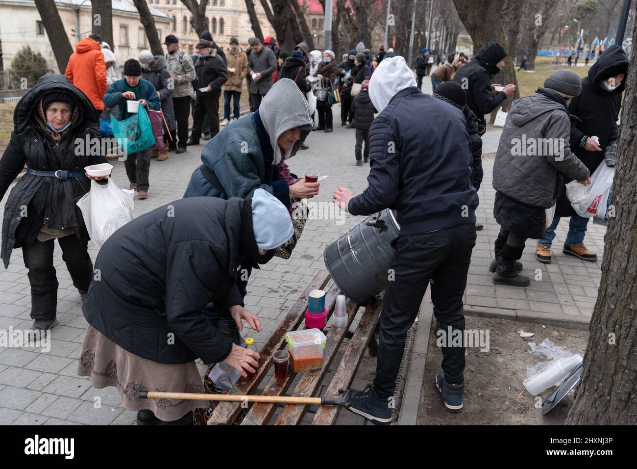 Volunteers distribute food to the homeless in one of the city streets ...
