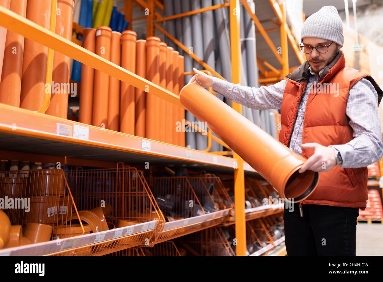 a male customer in a plumbing store chooses sewer pipes for his house ...