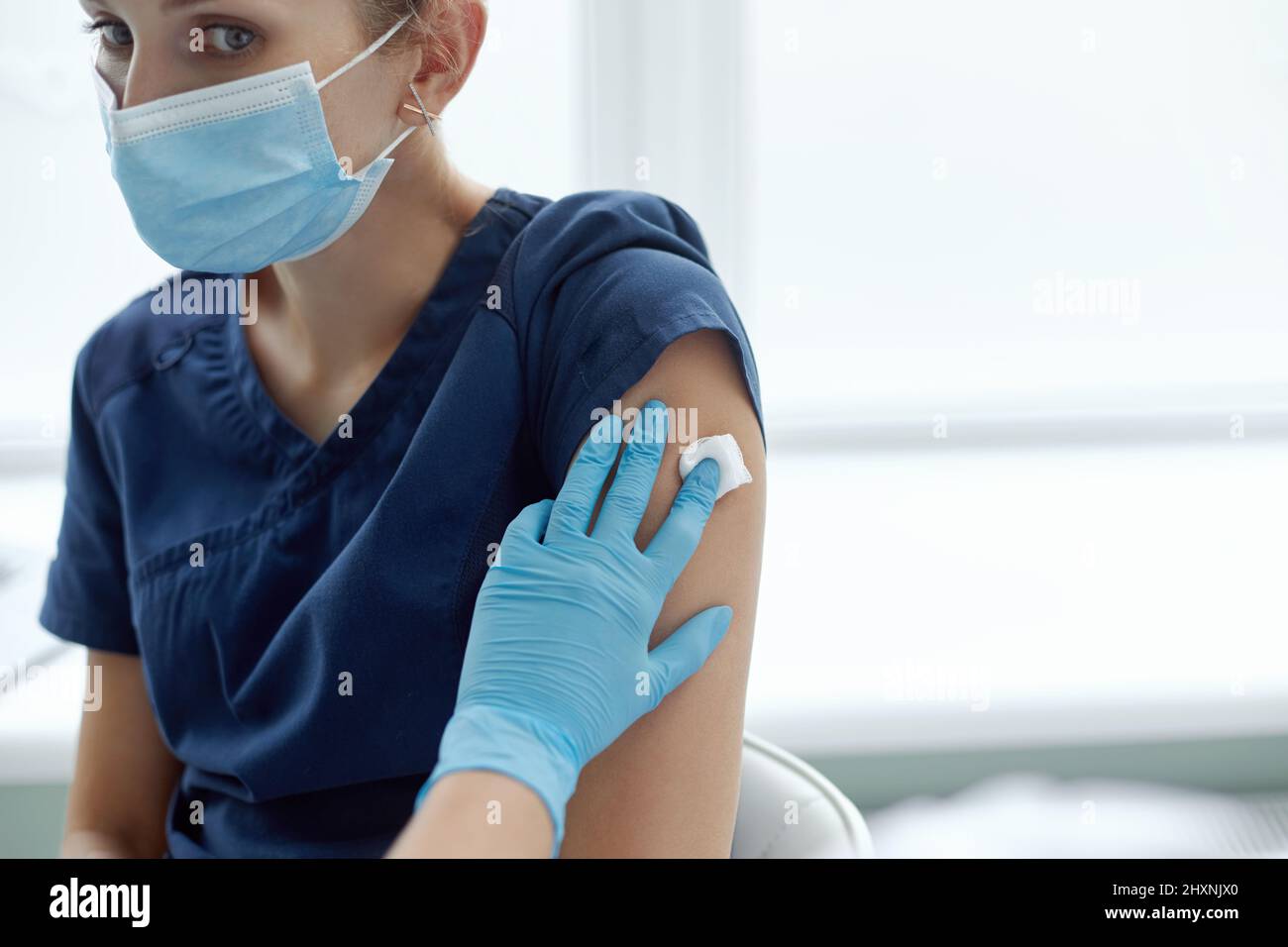 Woman in medical face mask getting injection at hospital. Doctor or ...