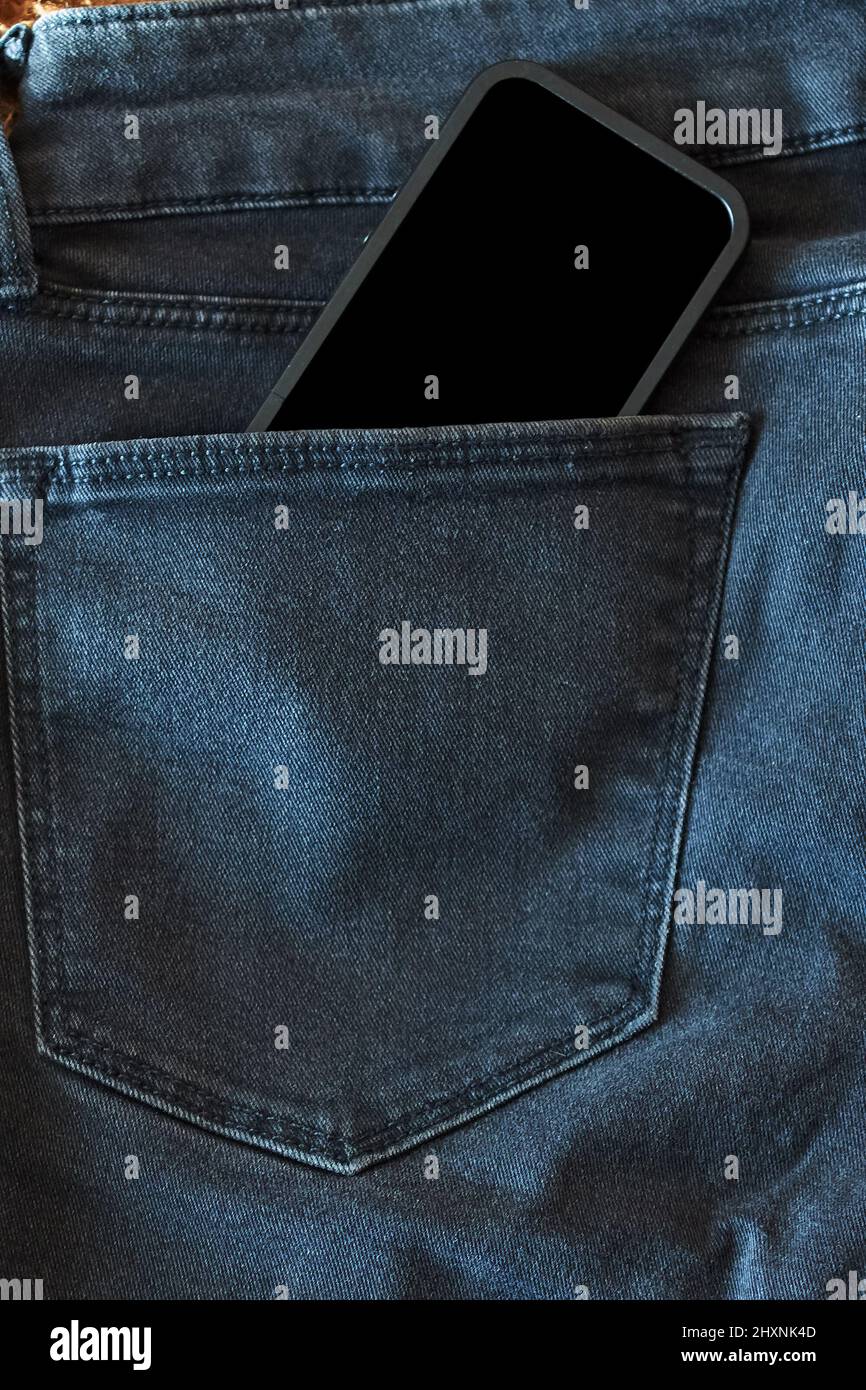 The upper part of old worn black jeans and a smartphone with a black ...