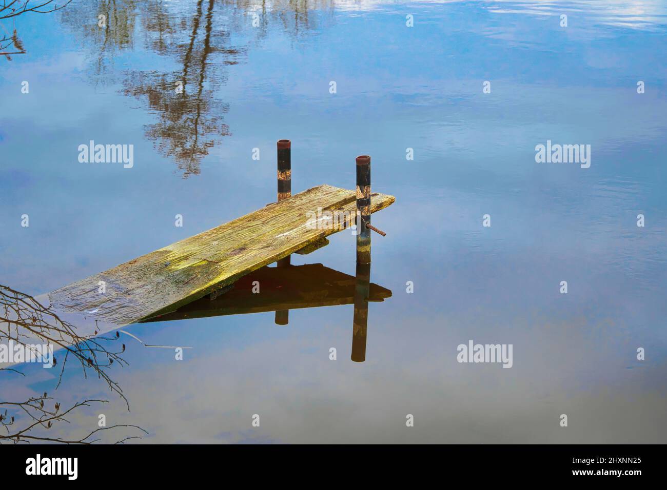Spring flooding, old broken sunken jetty in a tranquil lake with ...