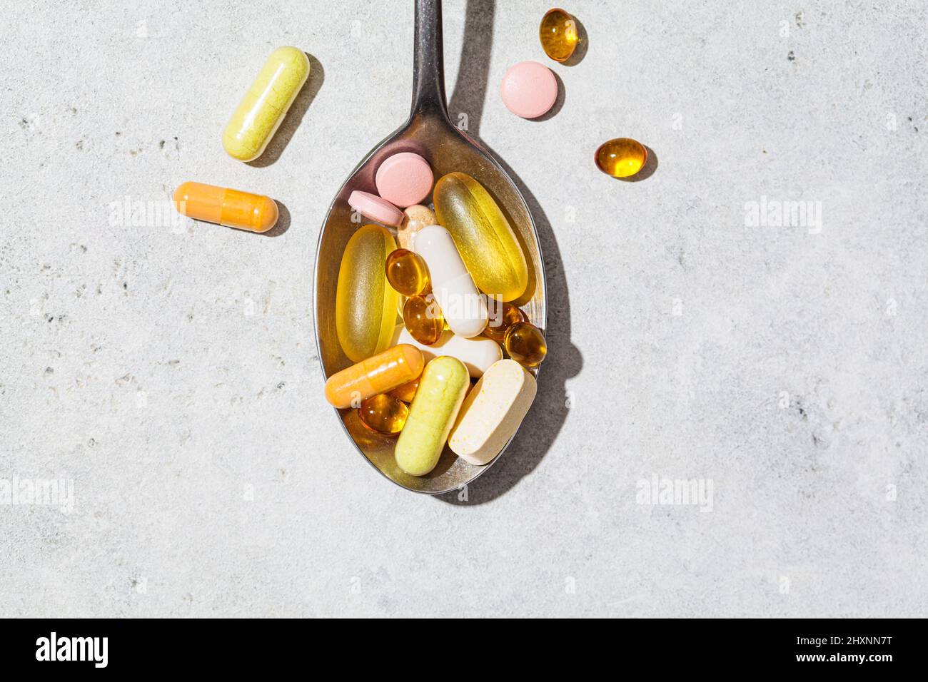 Different types of tablets, pills, capsules and vitamins in a spoon ...