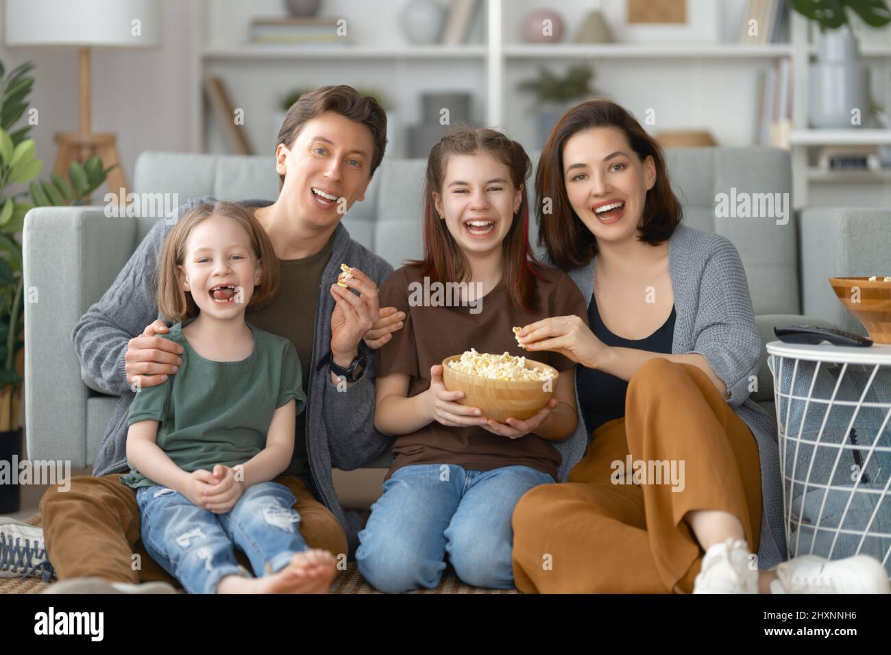Happy family watching projector, TV, movies with popcorn in the evening ...