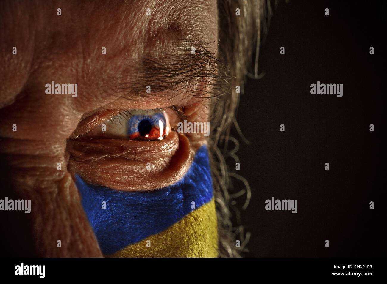 Close-up male eye with colors of Ukraine flag on his cheek. Stop war ...