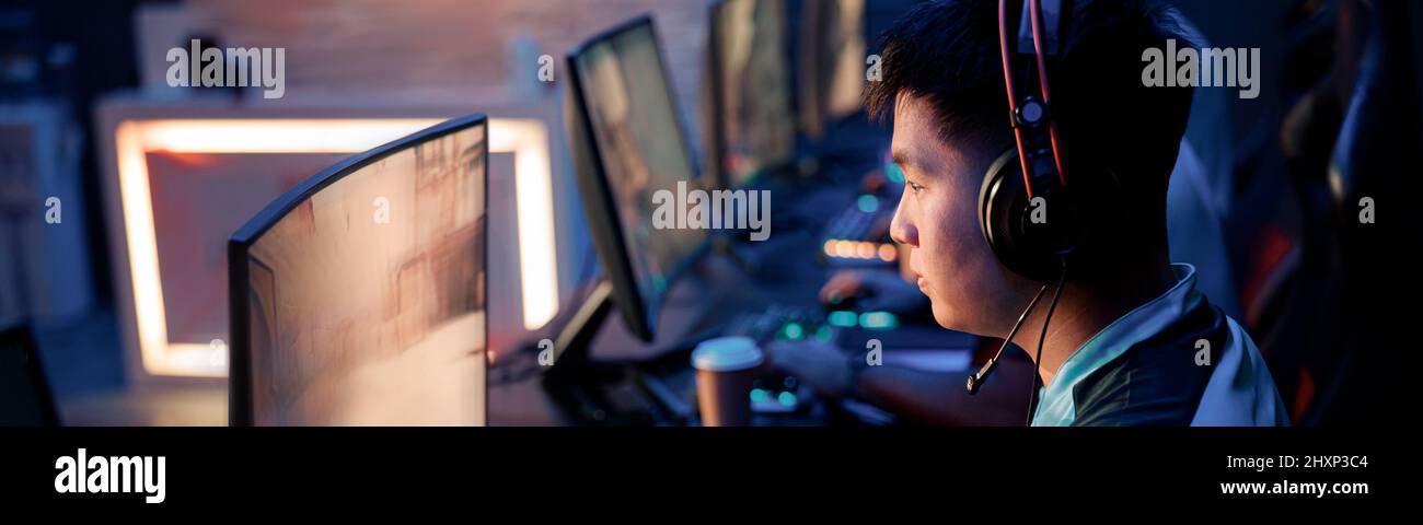 Smart gamer in headphones playing computer game in internet club Stock ...
