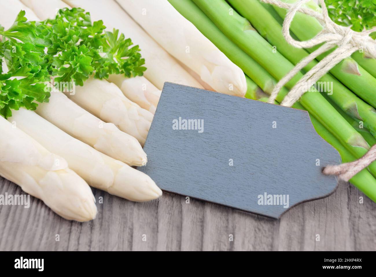 Seasonal fresh green and white asparagus with label on wooden ...