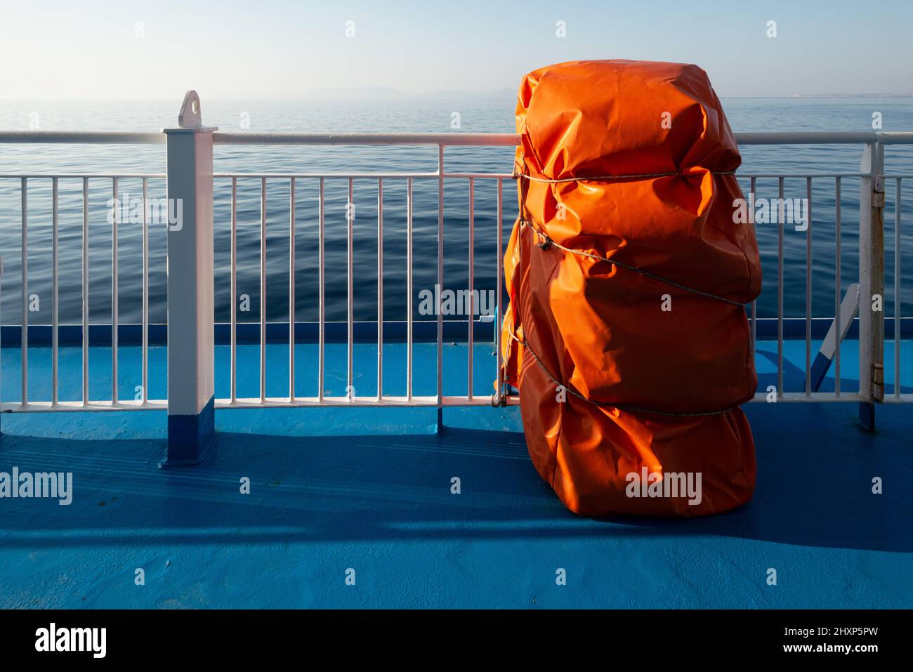 packed up orange life boat on deck of ferry with white railings and ...