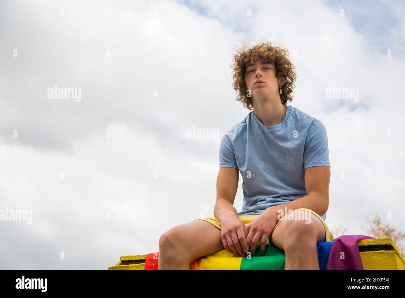 gay guy posing sitting on a gay pride flag Stock Photo - Alamy