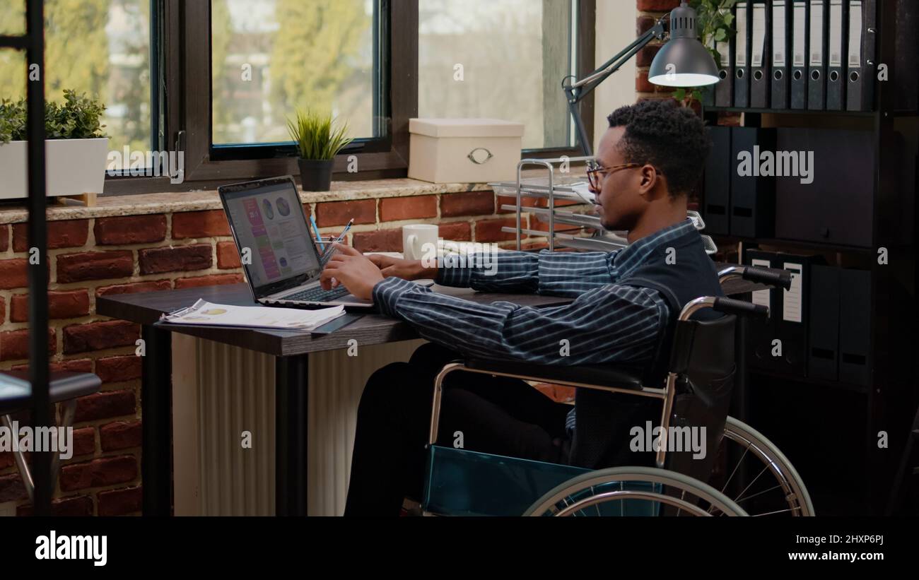 African american worker with chronic disability using laptop to plan ...