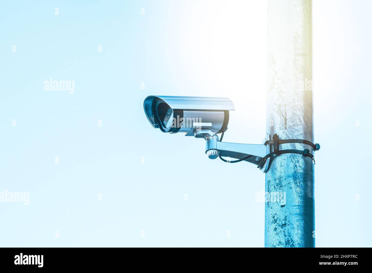Digital CCTV camera on a metal pole, blue pastel background. Security ...