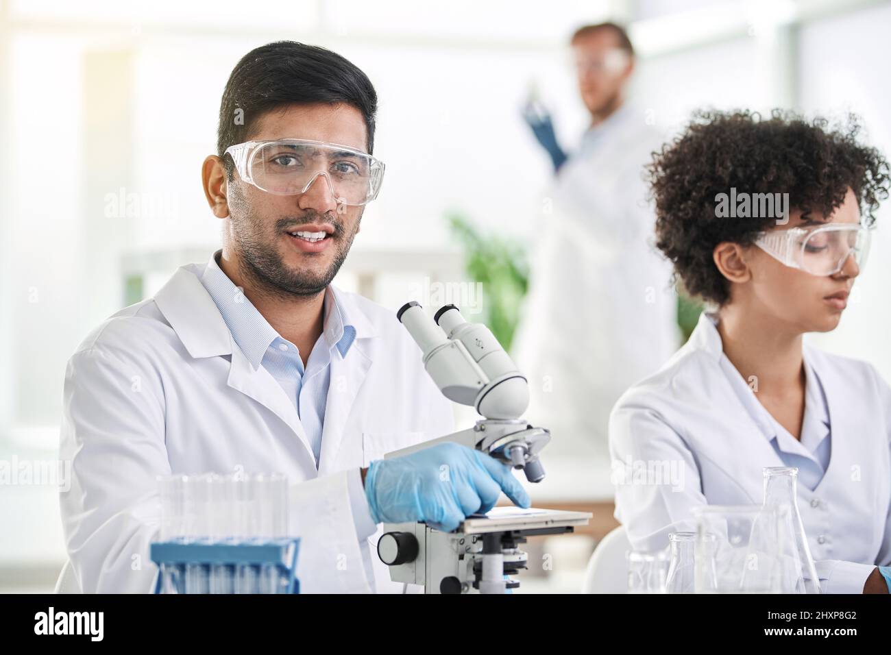 smiling scientist sitting in front of a laboratory microscope Stock ...