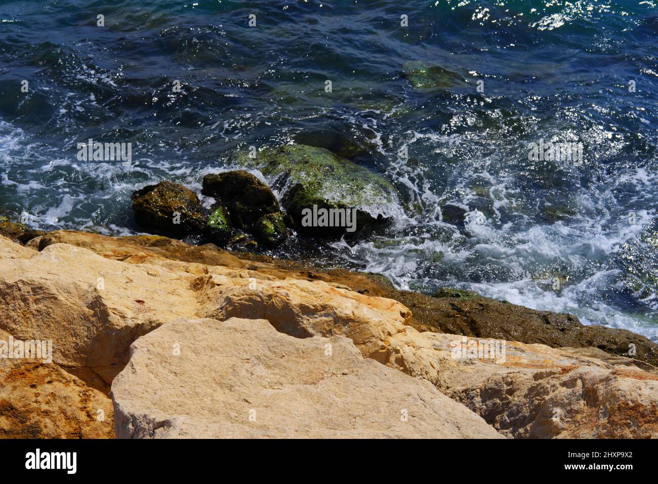 Small waves hitting wet rocks at seaside in a sunny day Stock Photo - Alamy