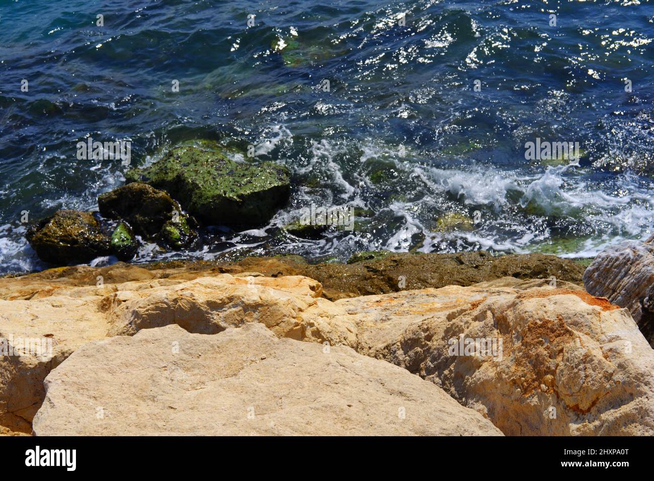 Small waves hitting wet rocks at seaside in a sunny day Stock Photo - Alamy