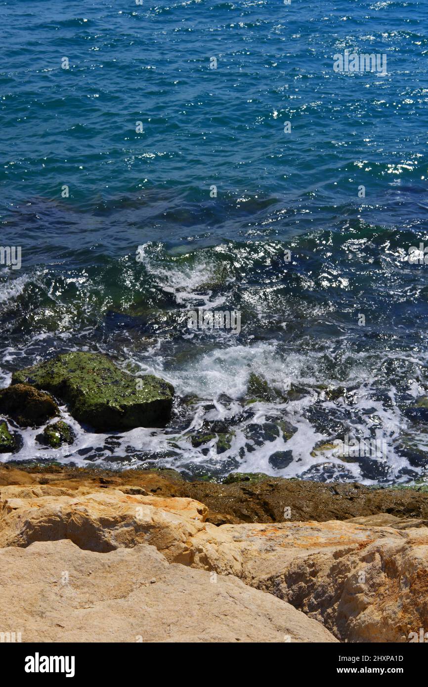 Small waves hitting wet rocks at seaside in a sunny day Stock Photo - Alamy