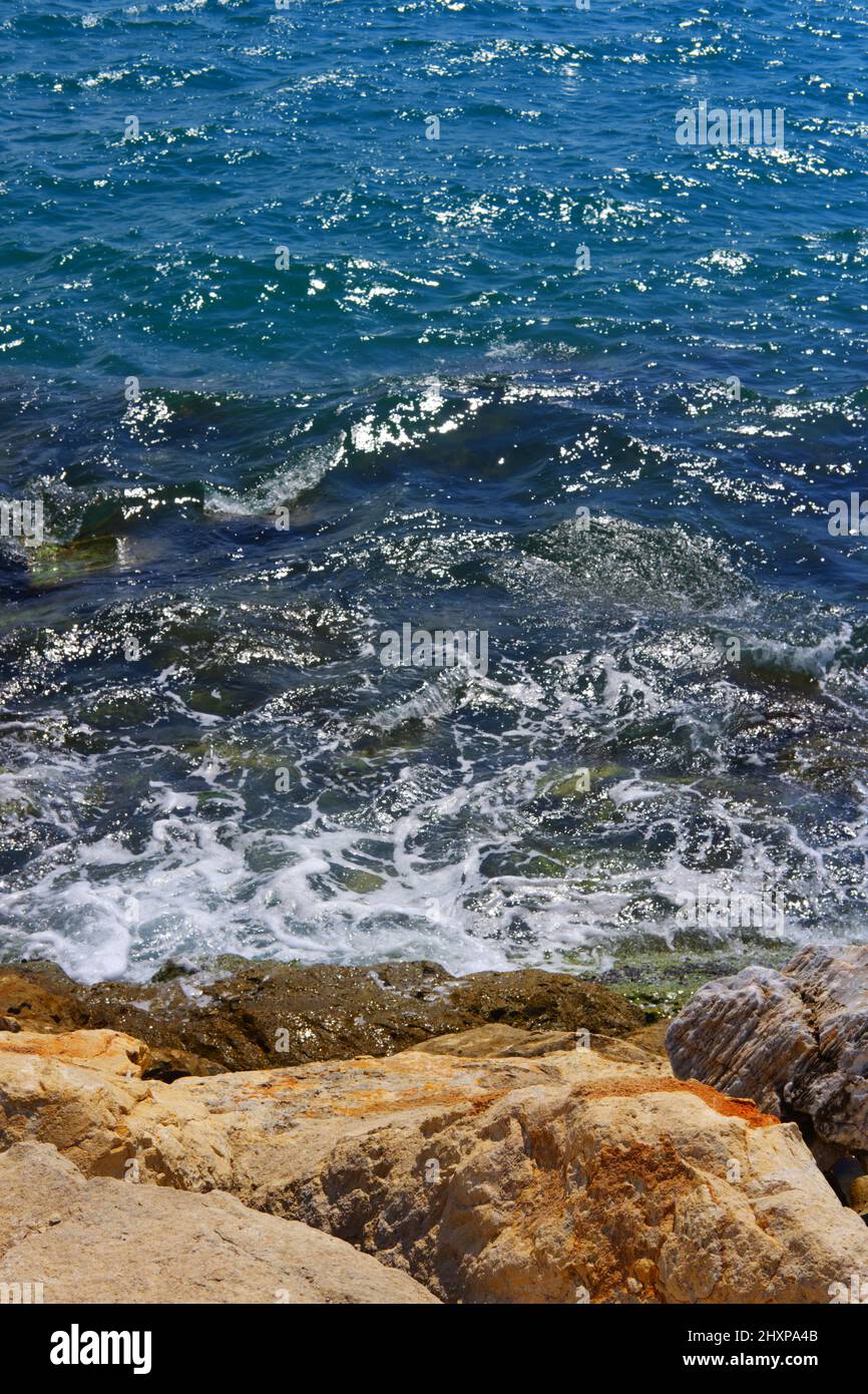 Small waves hitting wet rocks at seaside in a sunny day Stock Photo - Alamy
