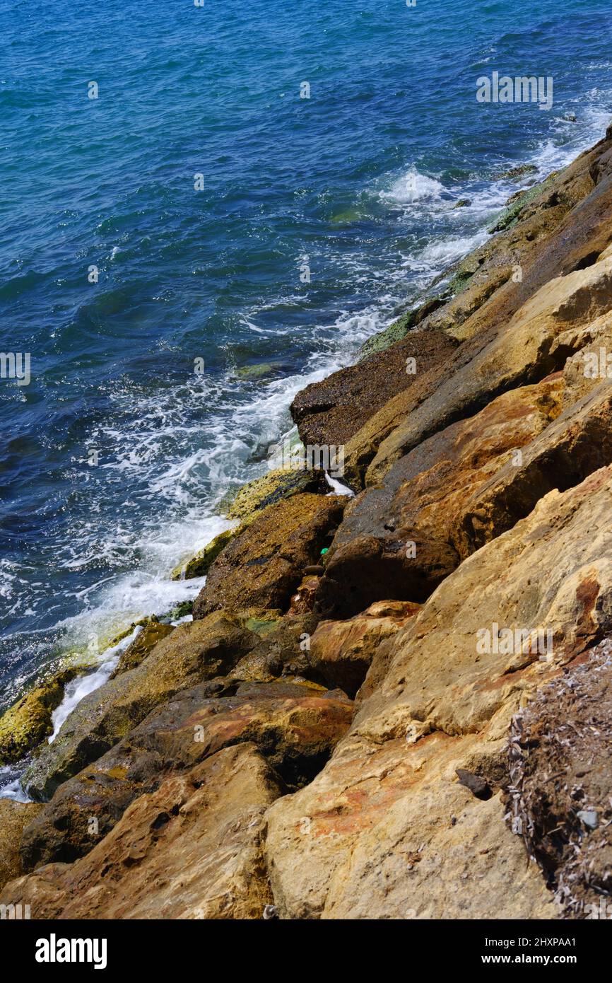 Small waves hitting wet rocks at seaside in a sunny day Stock Photo - Alamy