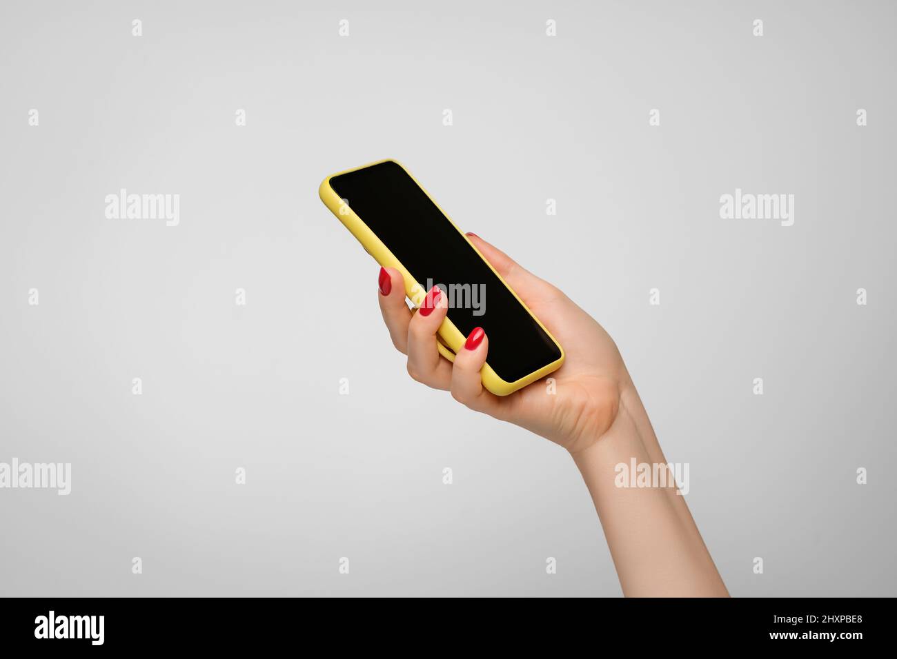 Mobile phone with a bright yellow case in a woman's hand with red nails ...