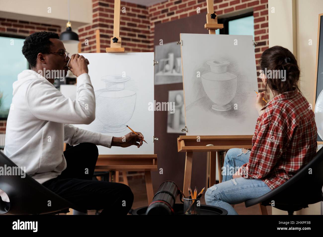 Artist painter woman working at sketching technique with collegue during art lesson in ...
