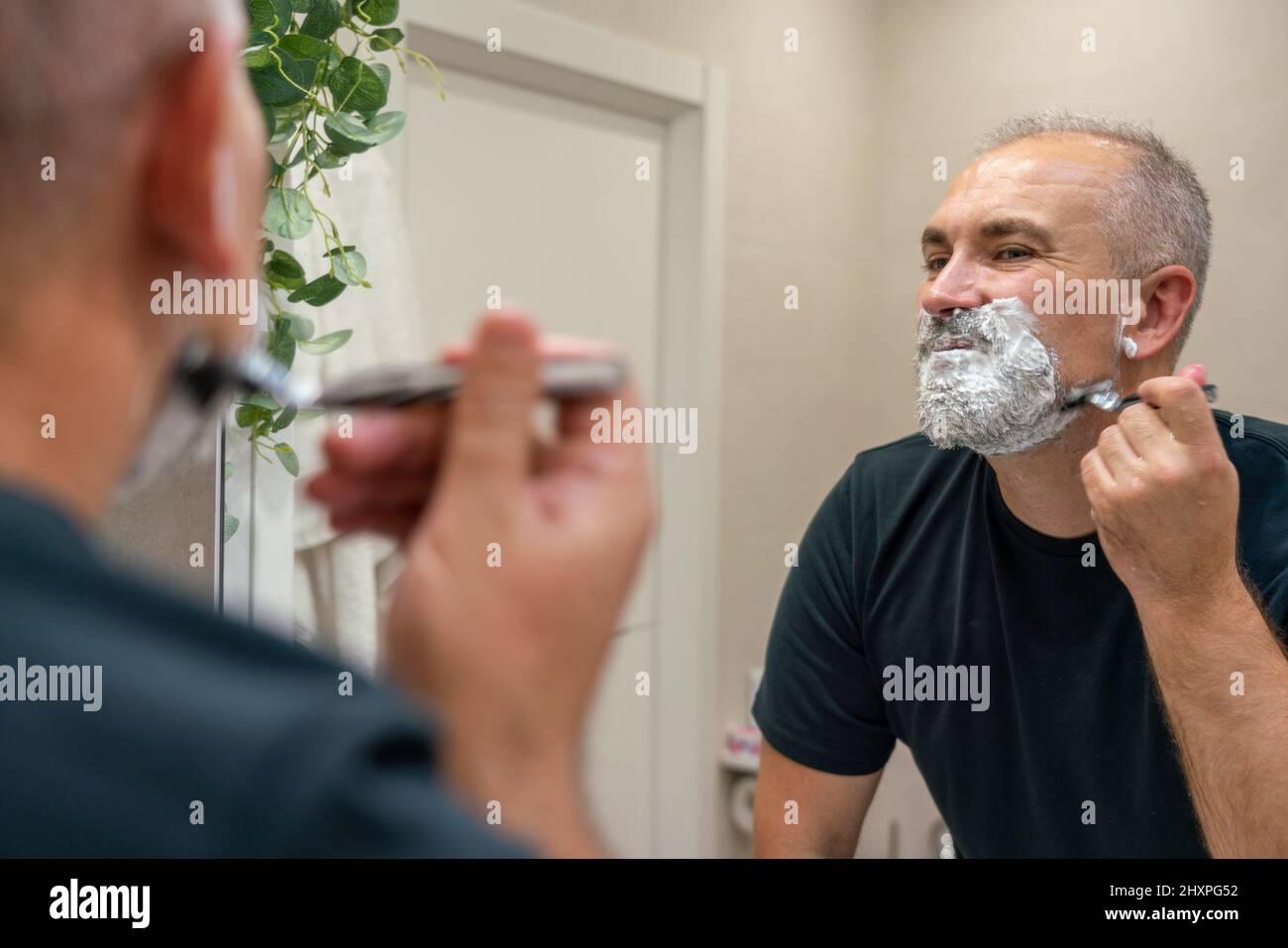 Shaving off beard and mustache. Man using razor to get rid of hairs on ...