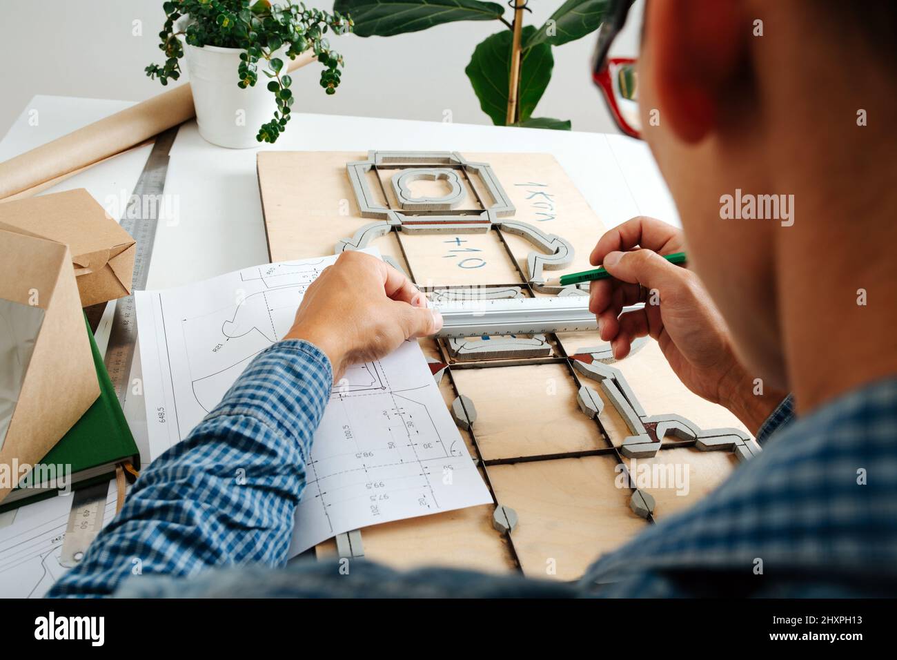 Keen box designer working on a blueprint, taking measures with a ruler ...