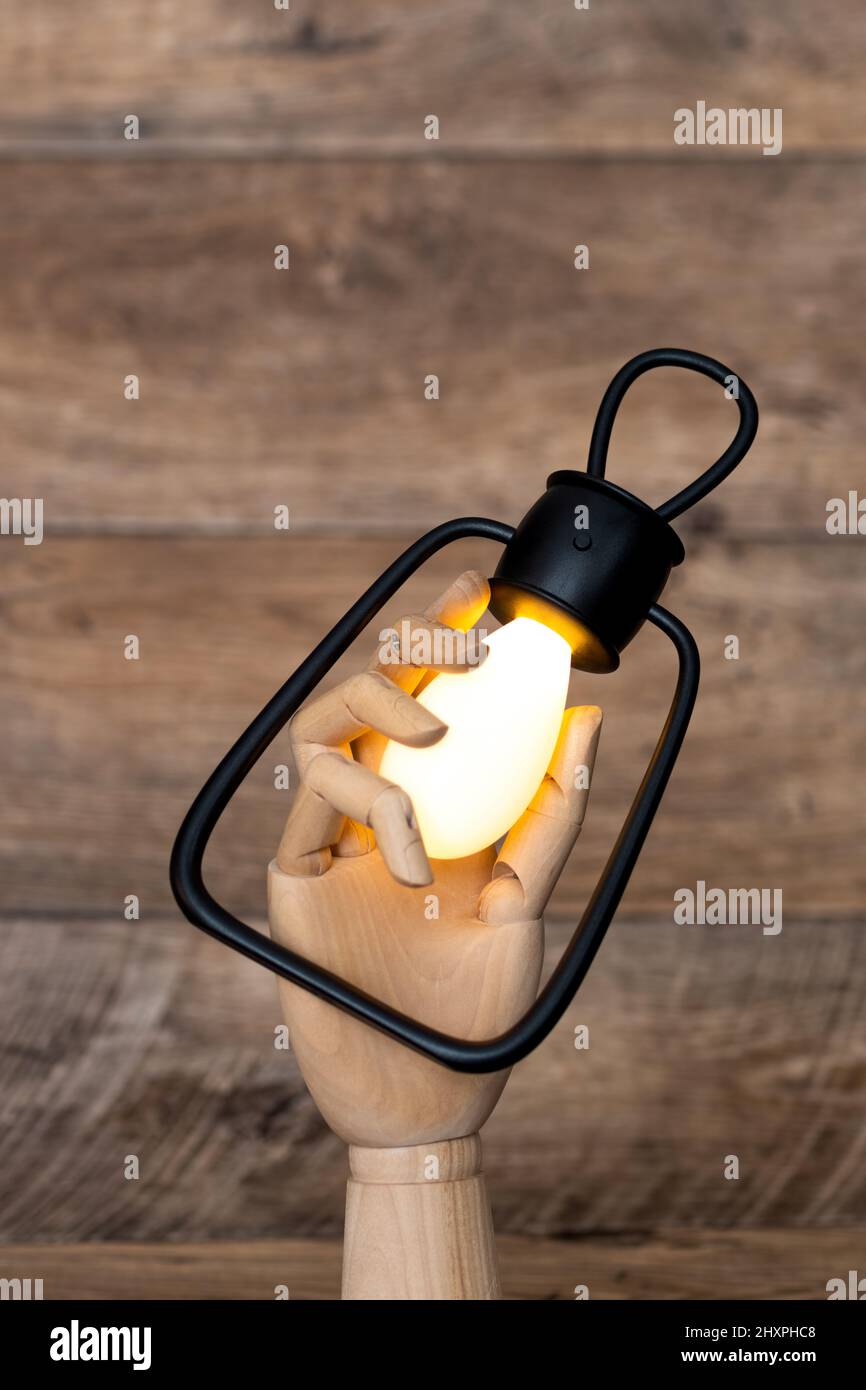 wooden hand of mannequin holding glowing light bulb lamp, vertical ...