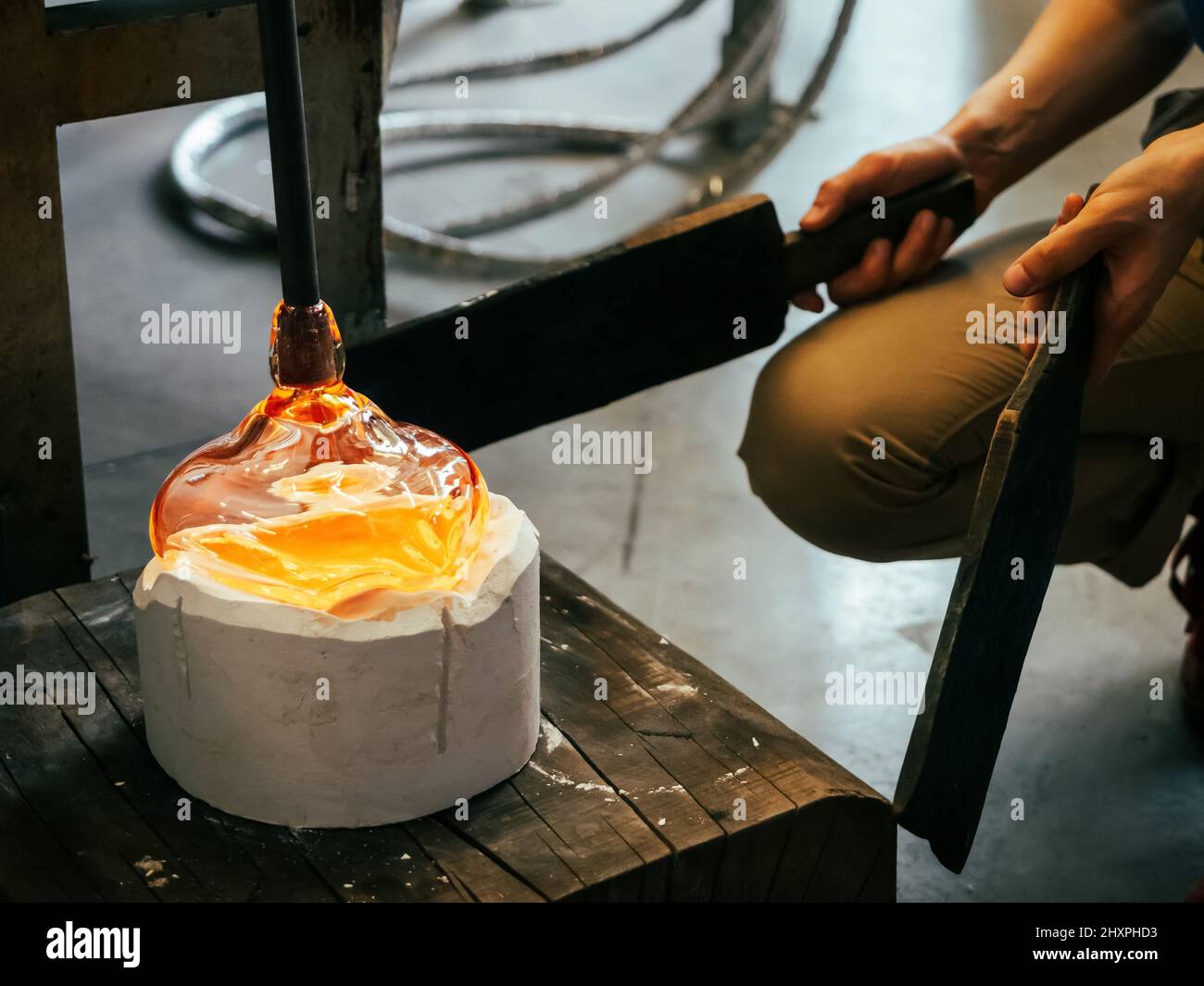 Close up of a glassblower artisan shaping the hot molten glass at ...