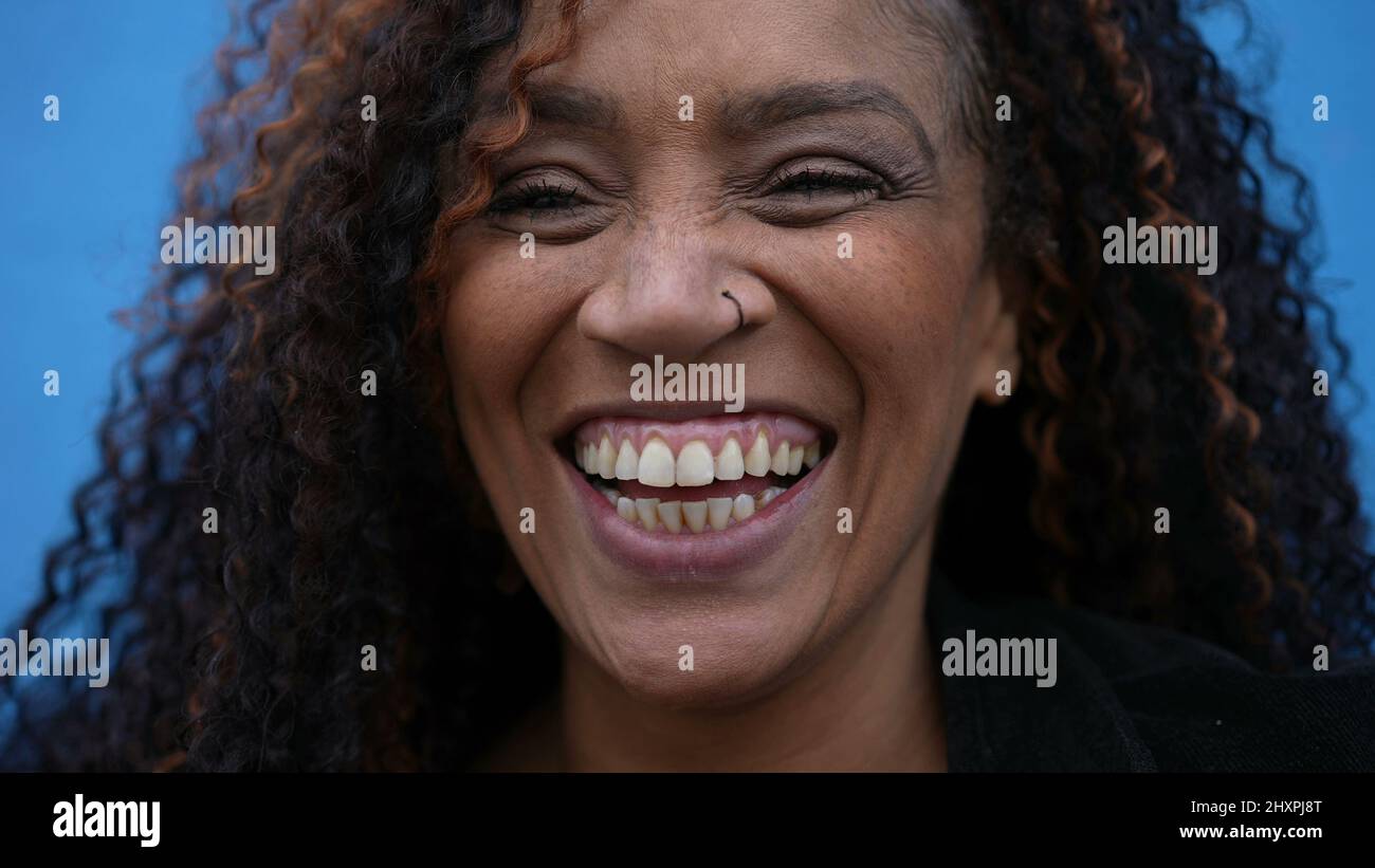 A happy diverse latin person in 40s laughing and smiling on blue ...