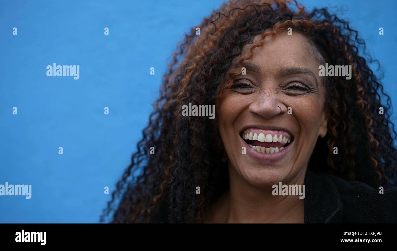 A happy diverse latin person in 40s laughing and smiling on blue ...