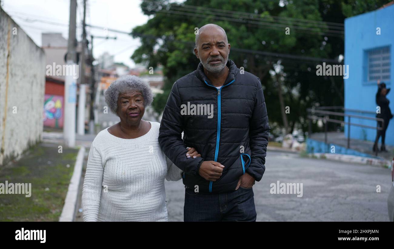 A son and senior mother walking together in street 80s parent Stock ...