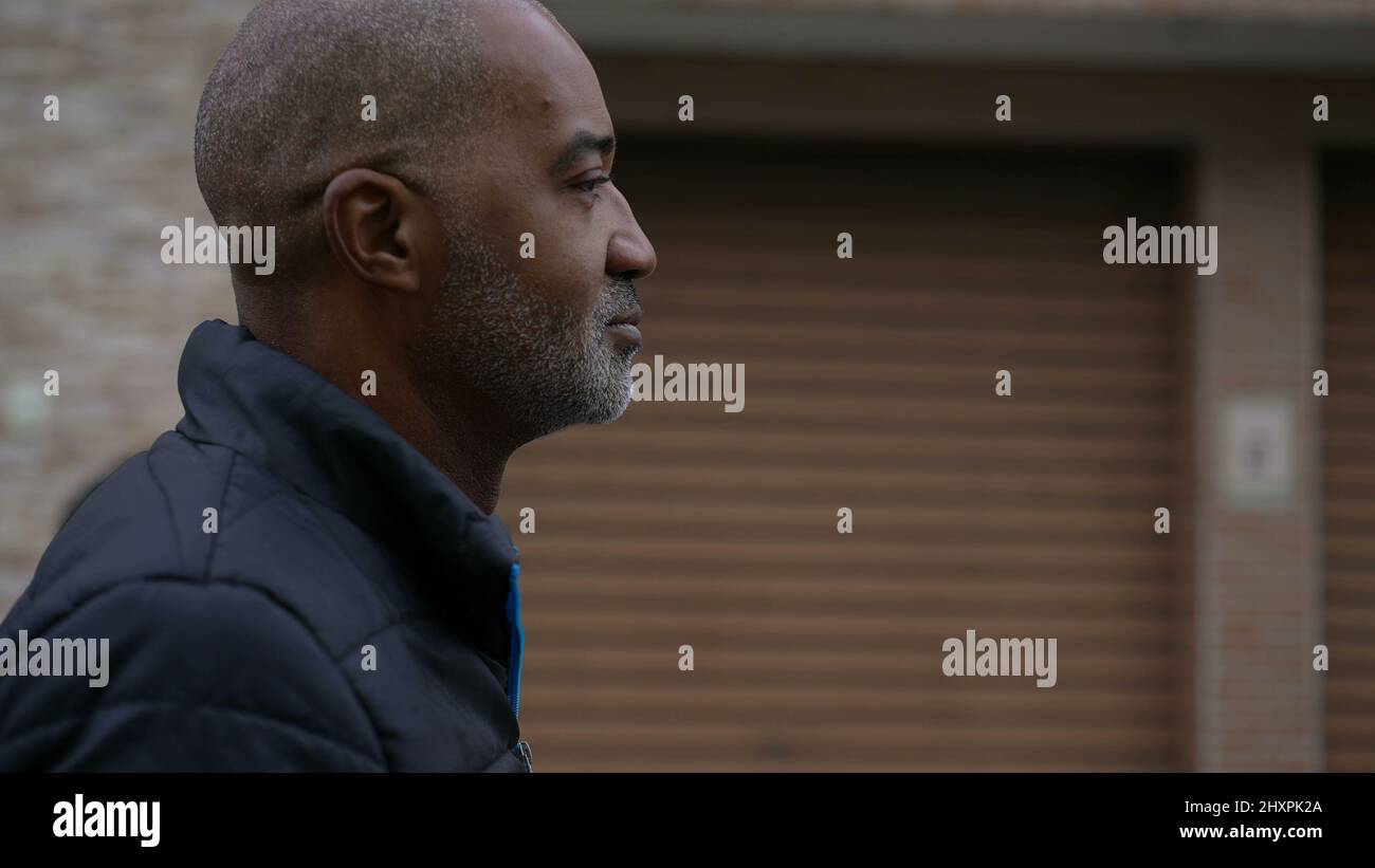 An introspective African man walking outside in street a contemplative ...