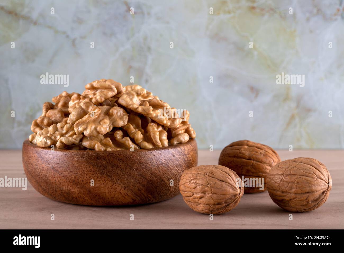 Bowl of walnuts and whole walnut kernels on color background Stock ...