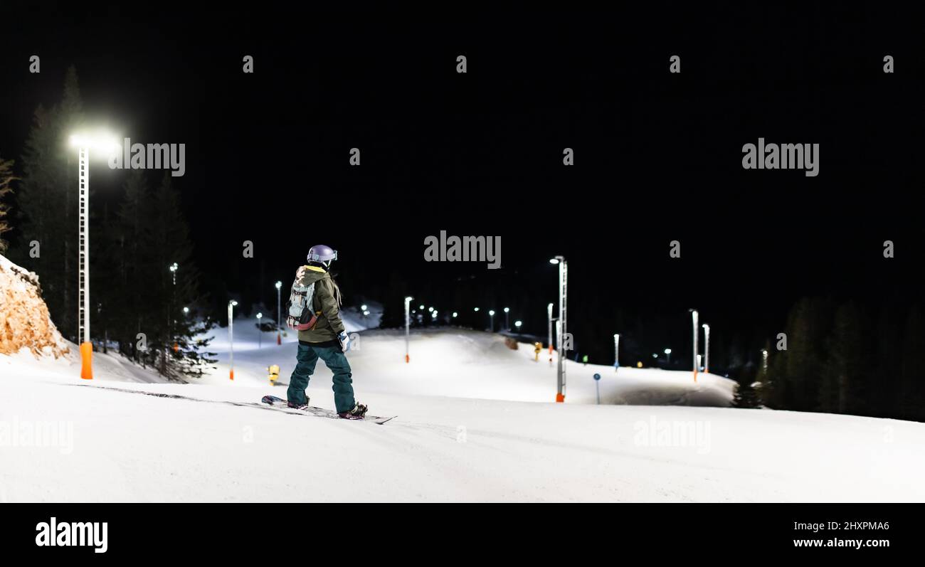 Snowboarder girl posing on slopes. Night skiing in winter resort Stock ...