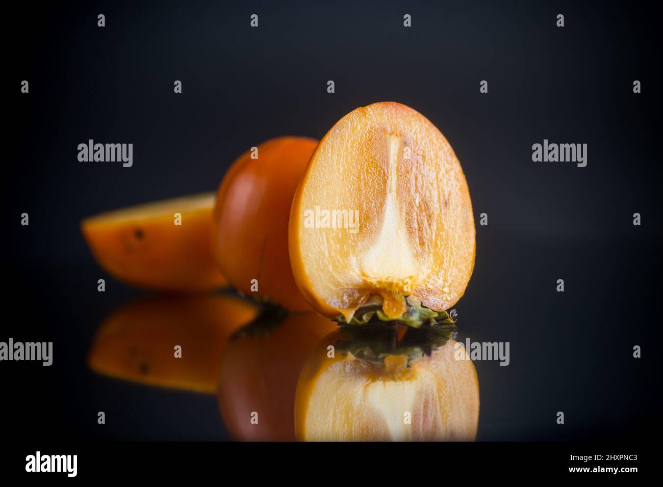 ripe cut half persimmon isolated on black Stock Photo - Alamy