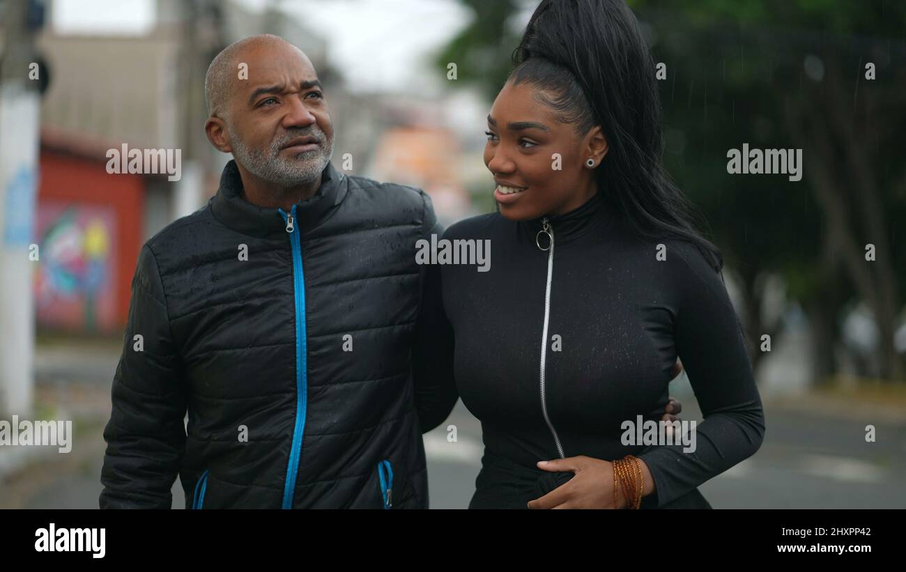 Father and daughter walking together talking outside in the drizzle ...