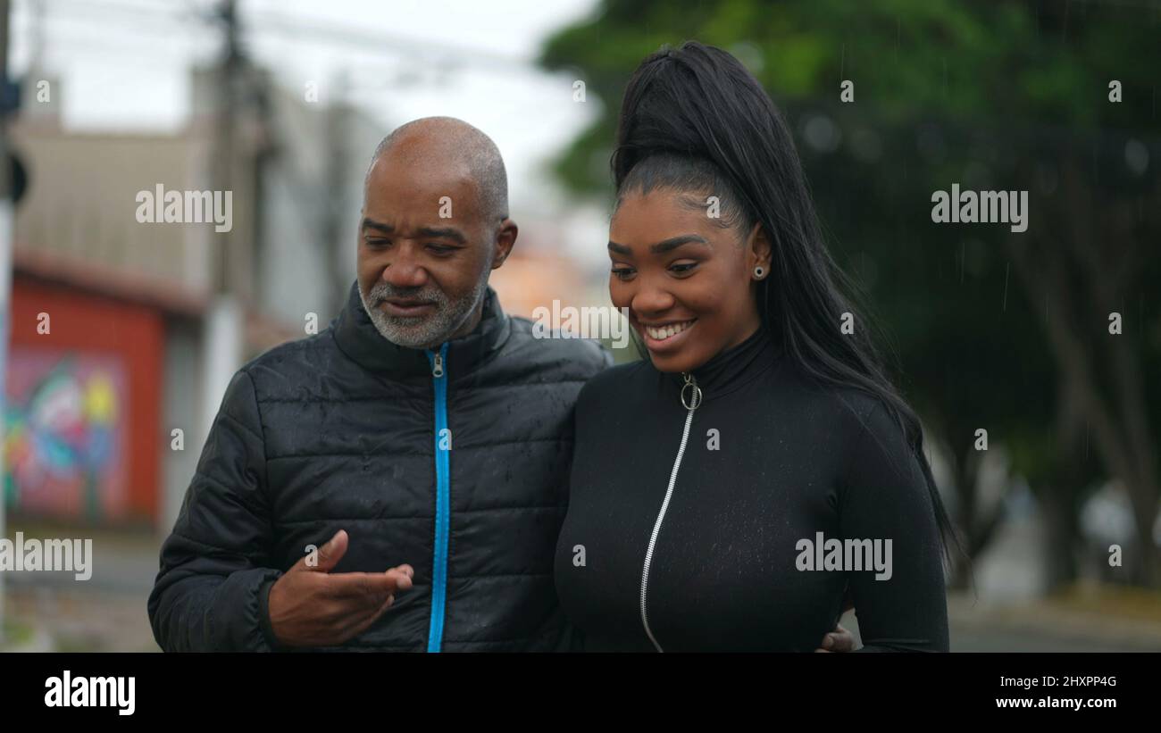 Father and daughter walking together talking outside in the drizzle ...