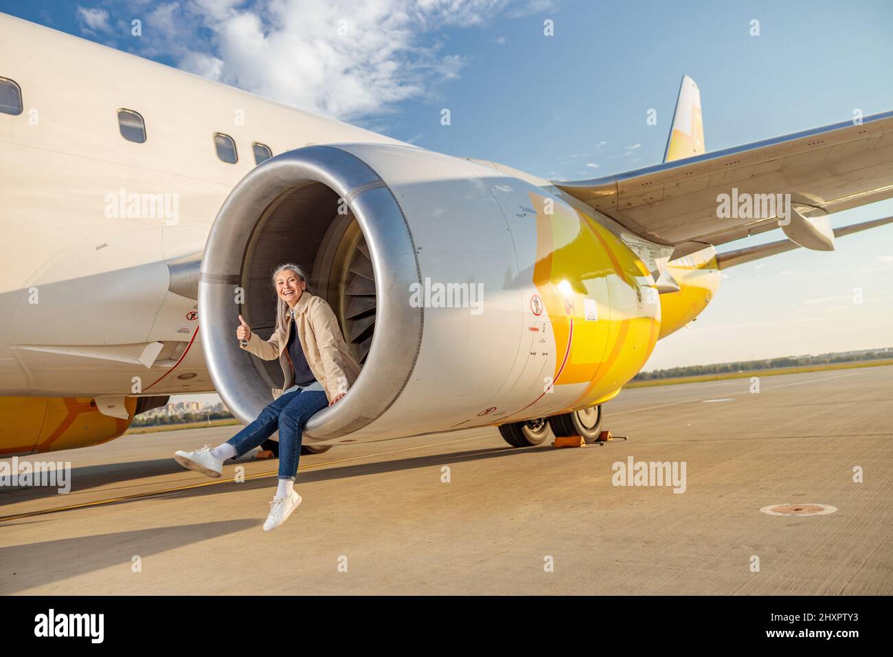 Joyful woman sitting in aircraft engine and giving thumbs up Stock ...