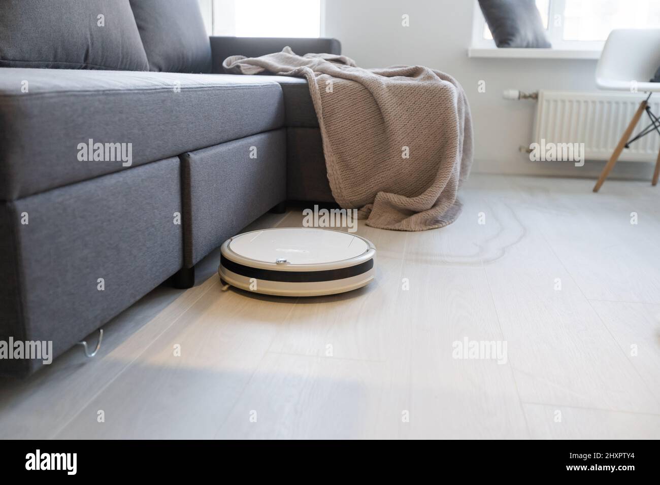 Smart House. Vacuum cleaner robot runs on wood floor in a living room ...