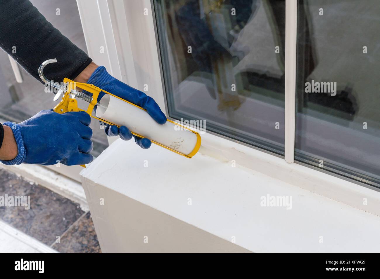 Worker is applying polyurethane foam to fill gap between sash and ...