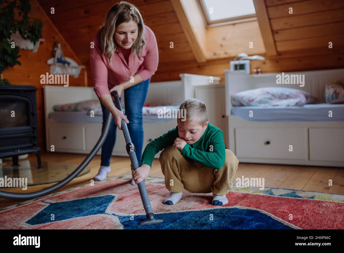 Boy with Down syndrome with his mother vacuum cleaning at home Stock ...