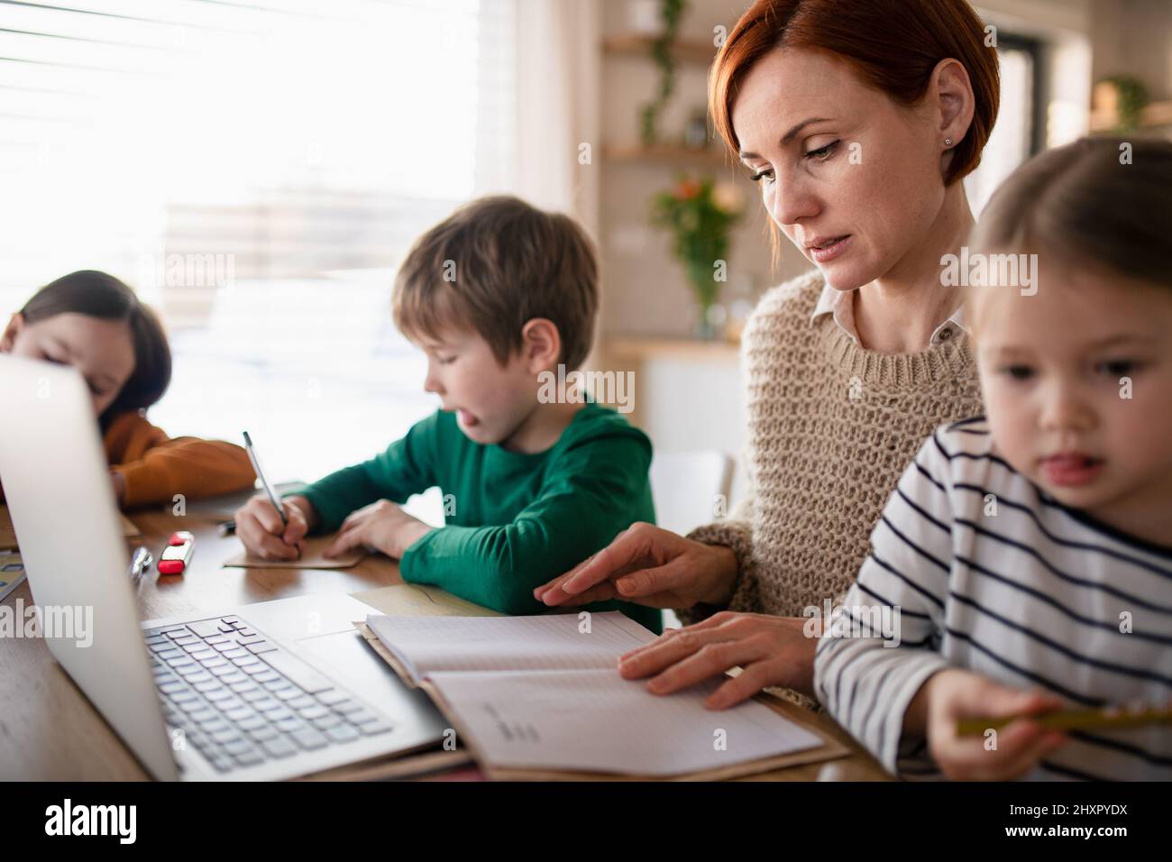 Mother of little children working on laptop when distance learning and ...