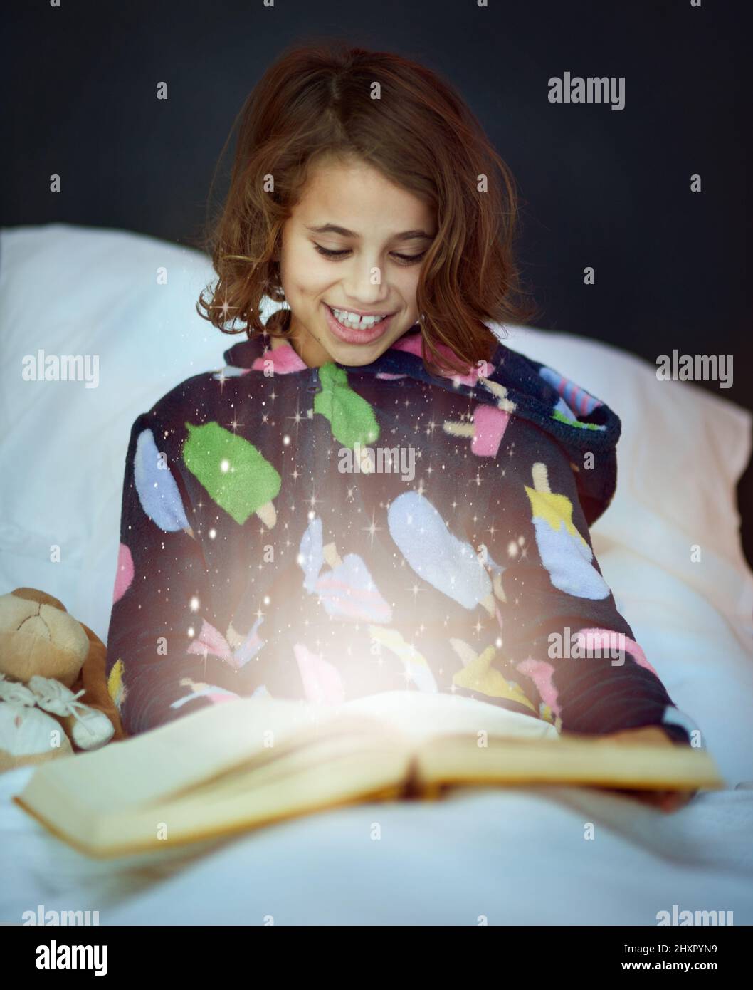 The story comes to life. Cropped shot of a girl reading a book in bed ...