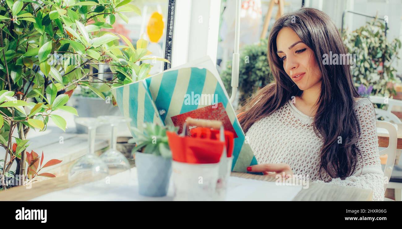 Beautiful woman looking at menu and ordering foods in restaurant. Close ...
