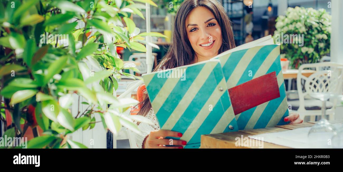 Beautiful woman looking at menu and ordering foods in restaurant. Close ...