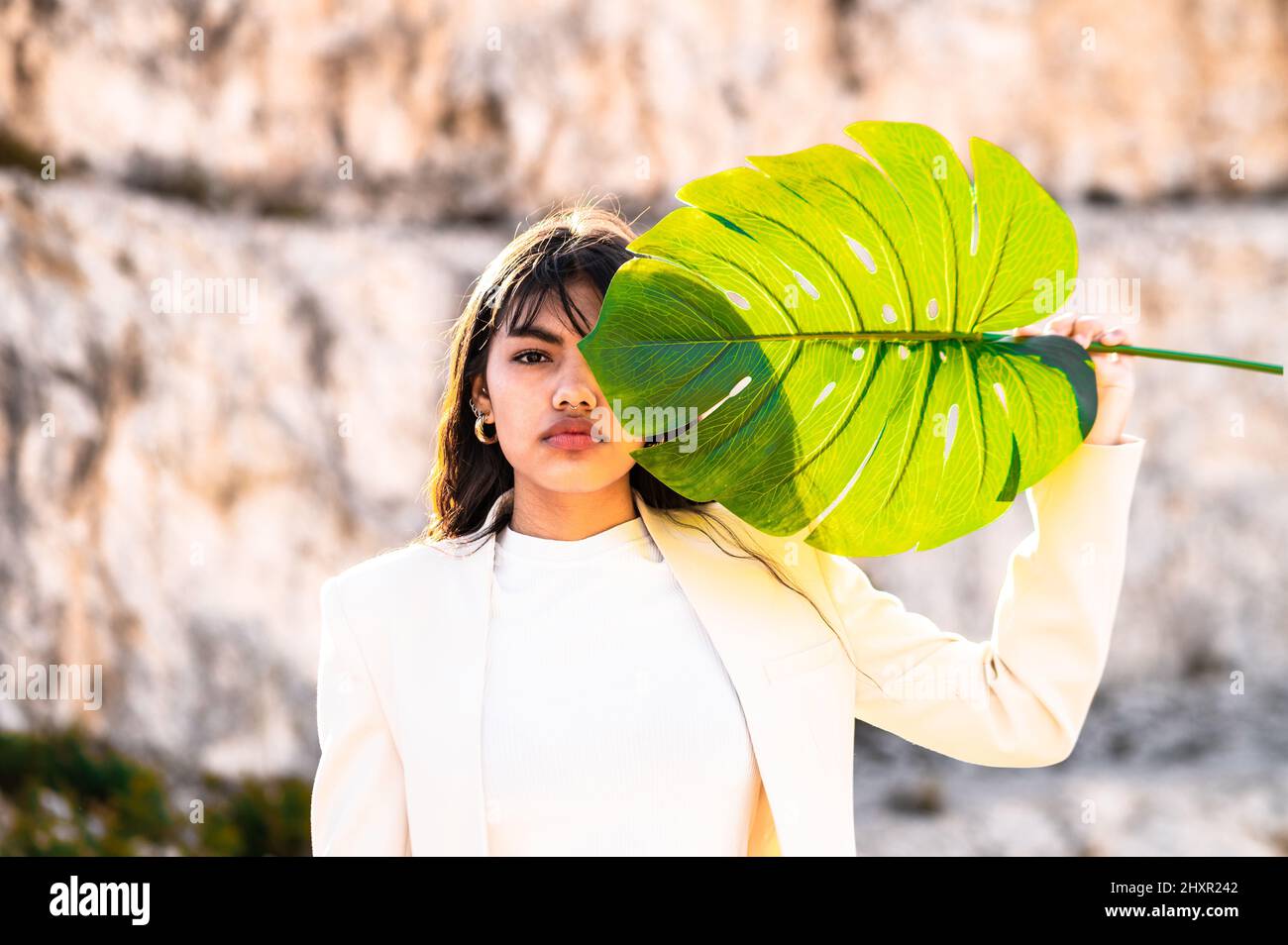 Elegant woman dressed in a white suit covering half her face with a ...
